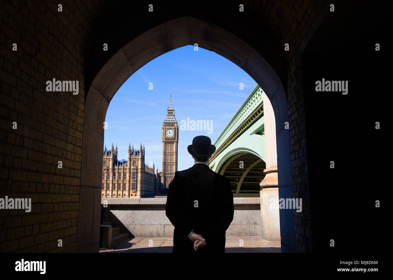 Rear view of man wearing black coat and Bowler hat standing near ...
