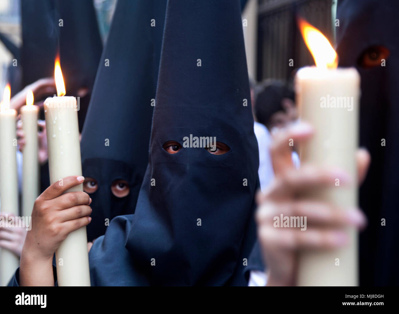 Close up of children dressed in dark robes with lit candles at a ...