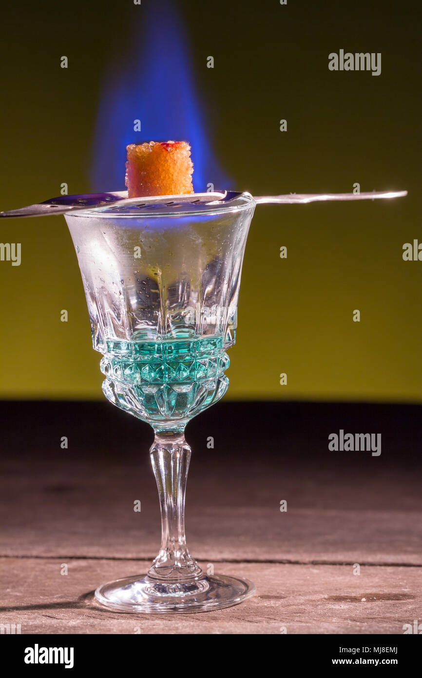 Burning sugar on spoon in glass of absinthe Stock Photo - Alamy