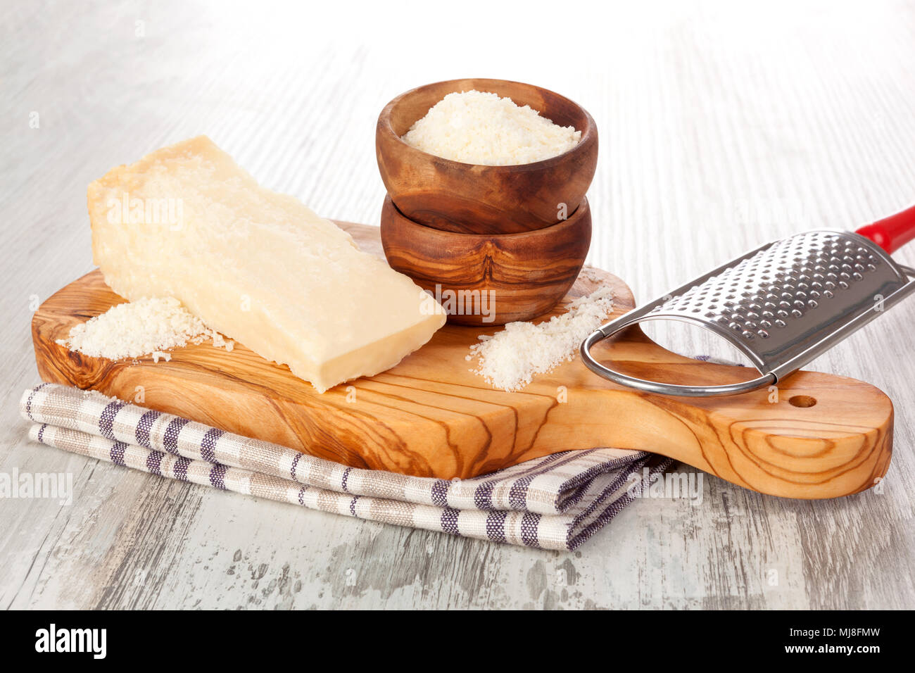 Grated and whole Parmesan cheese with grater on wooden table Stock ...