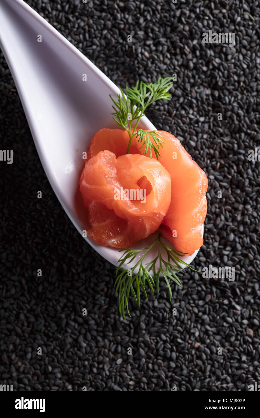 Slice of salted salmon with dill on the background of black sesame. Top ...
