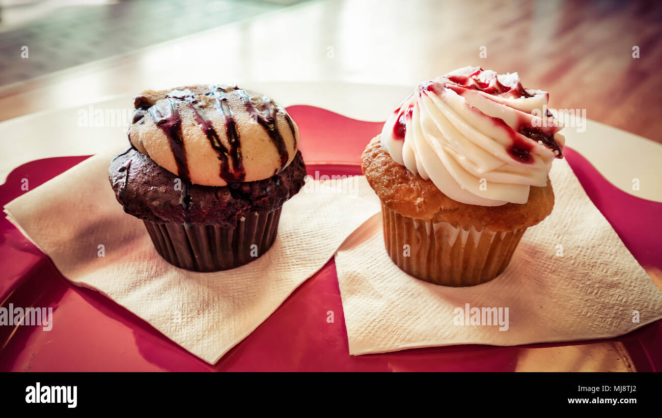 A frosted chocolate and raspberry cupcake sitting on a tray at a bakery ...