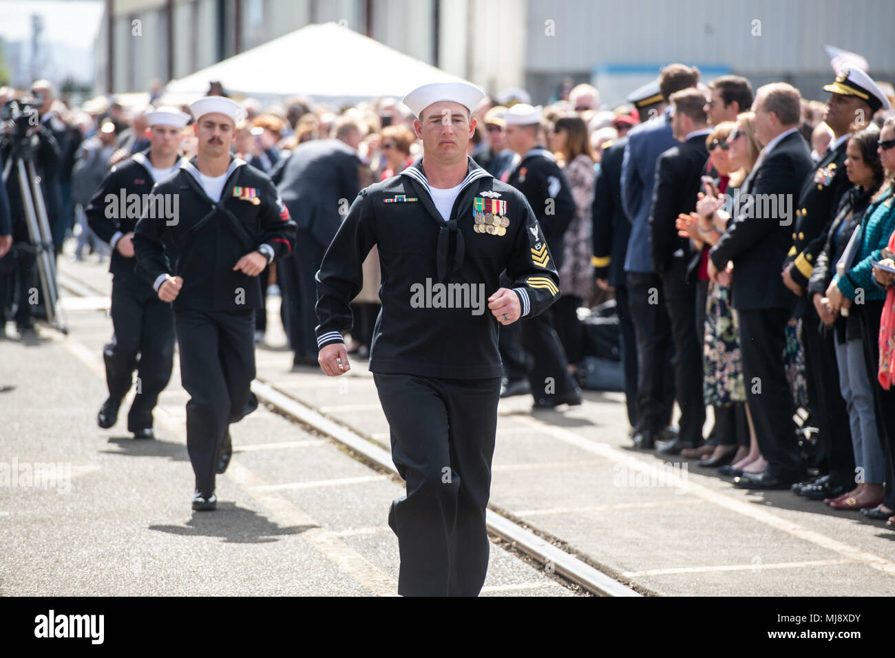 U.S. Navy Sailors run to crew the USS Portland (LPD 27) during it’s ...