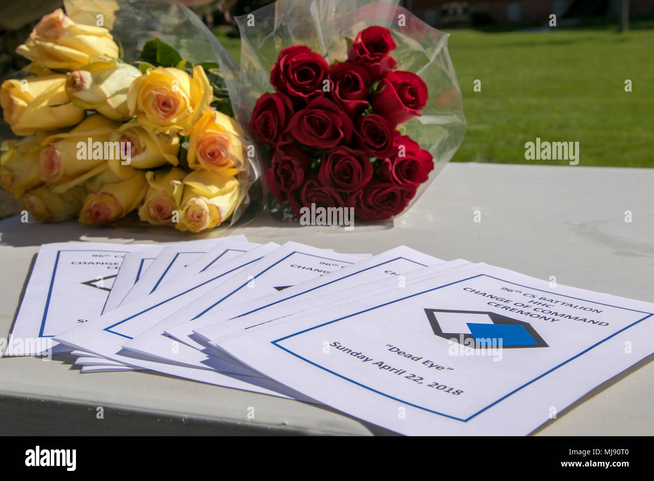 Two bouquets of roses and a stack of programs are placed on a table to ...