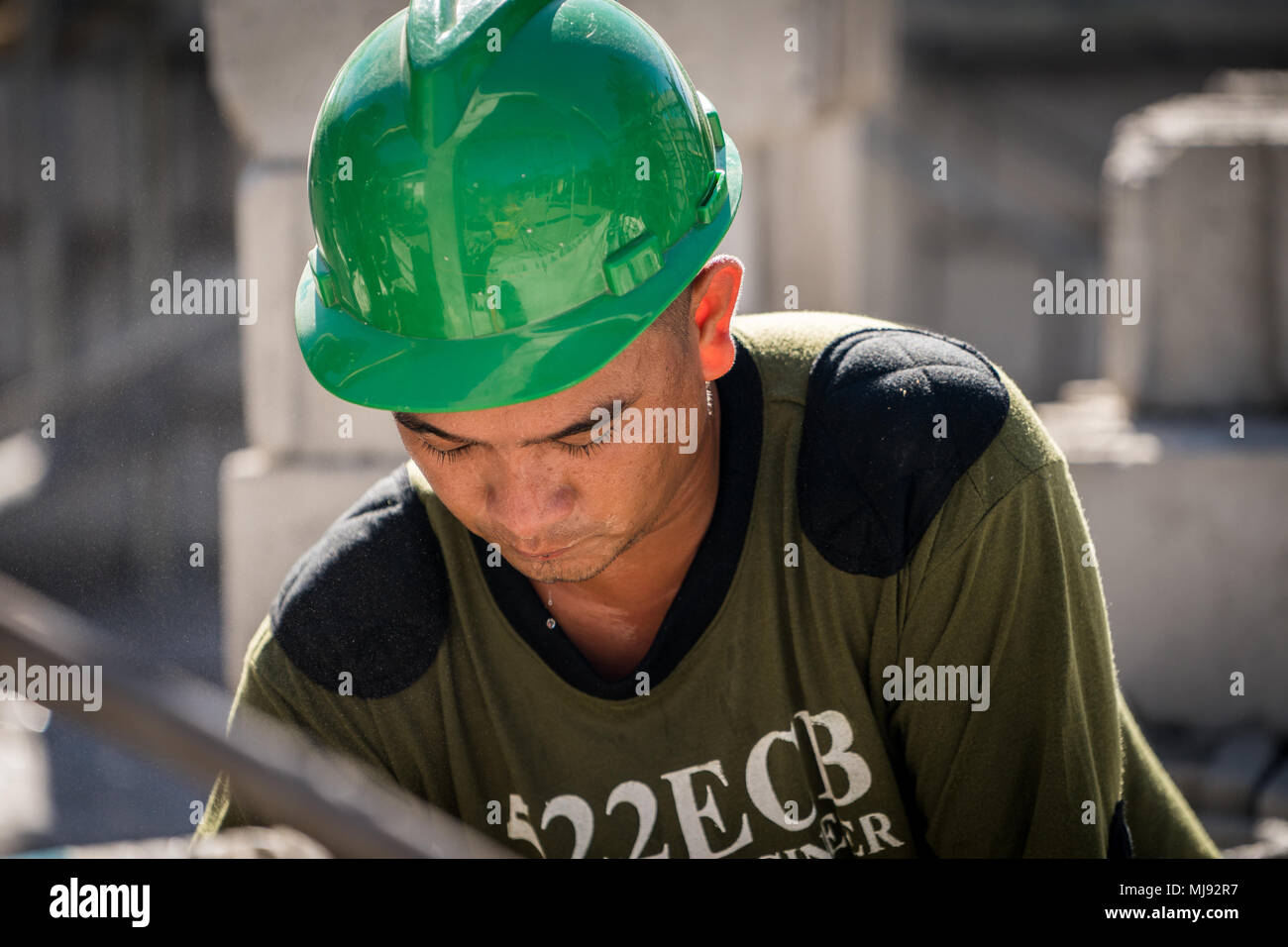 Sweat drips from Philippine Army Cpl. Elton Dela Pena's face while he chops concrete blocks ...
