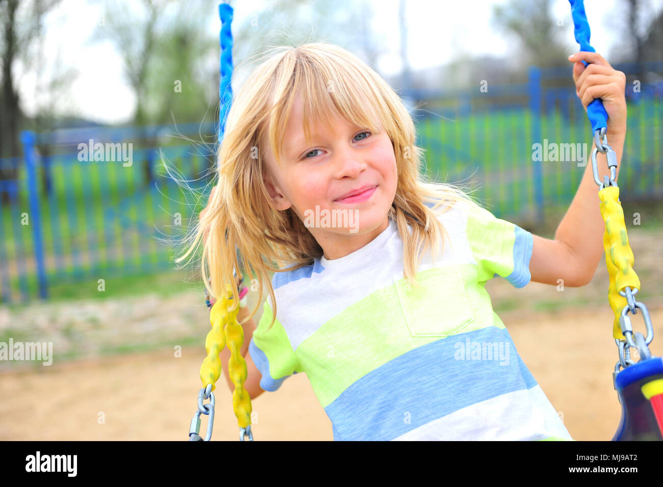 Happy boy on swing at the playground Stock Photo - Alamy