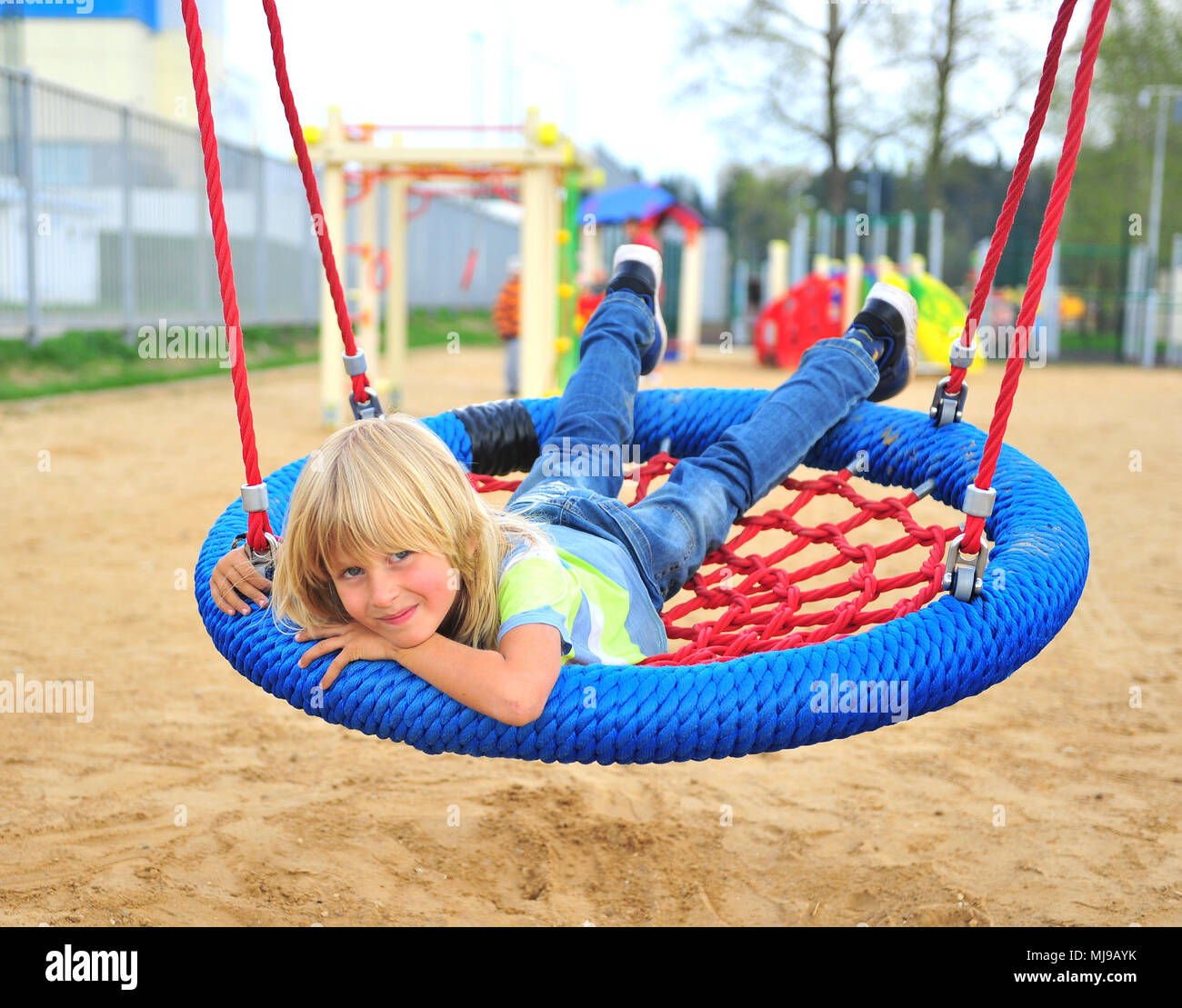Smiling boy lying on the swing at playground Stock Photo - Alamy