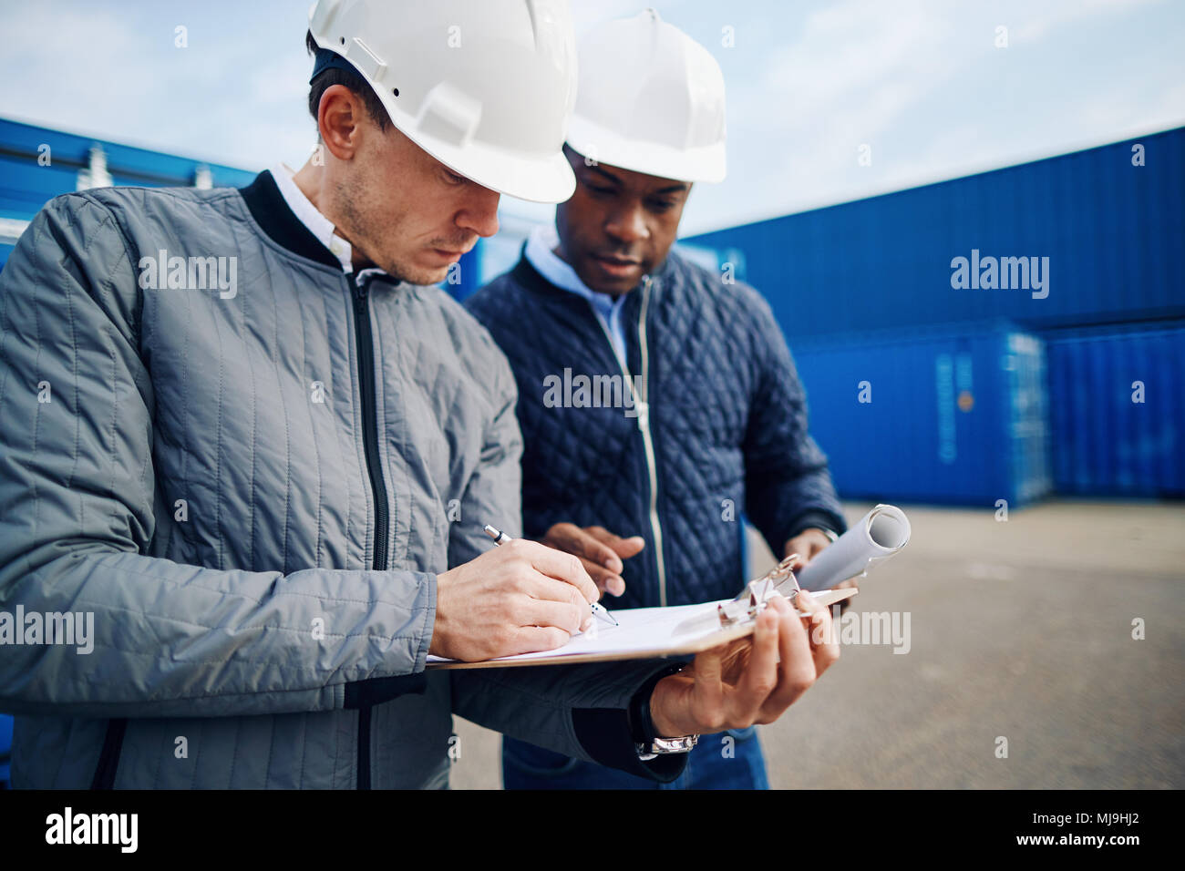Two engineers standing by shipping containers on a large commercial ...