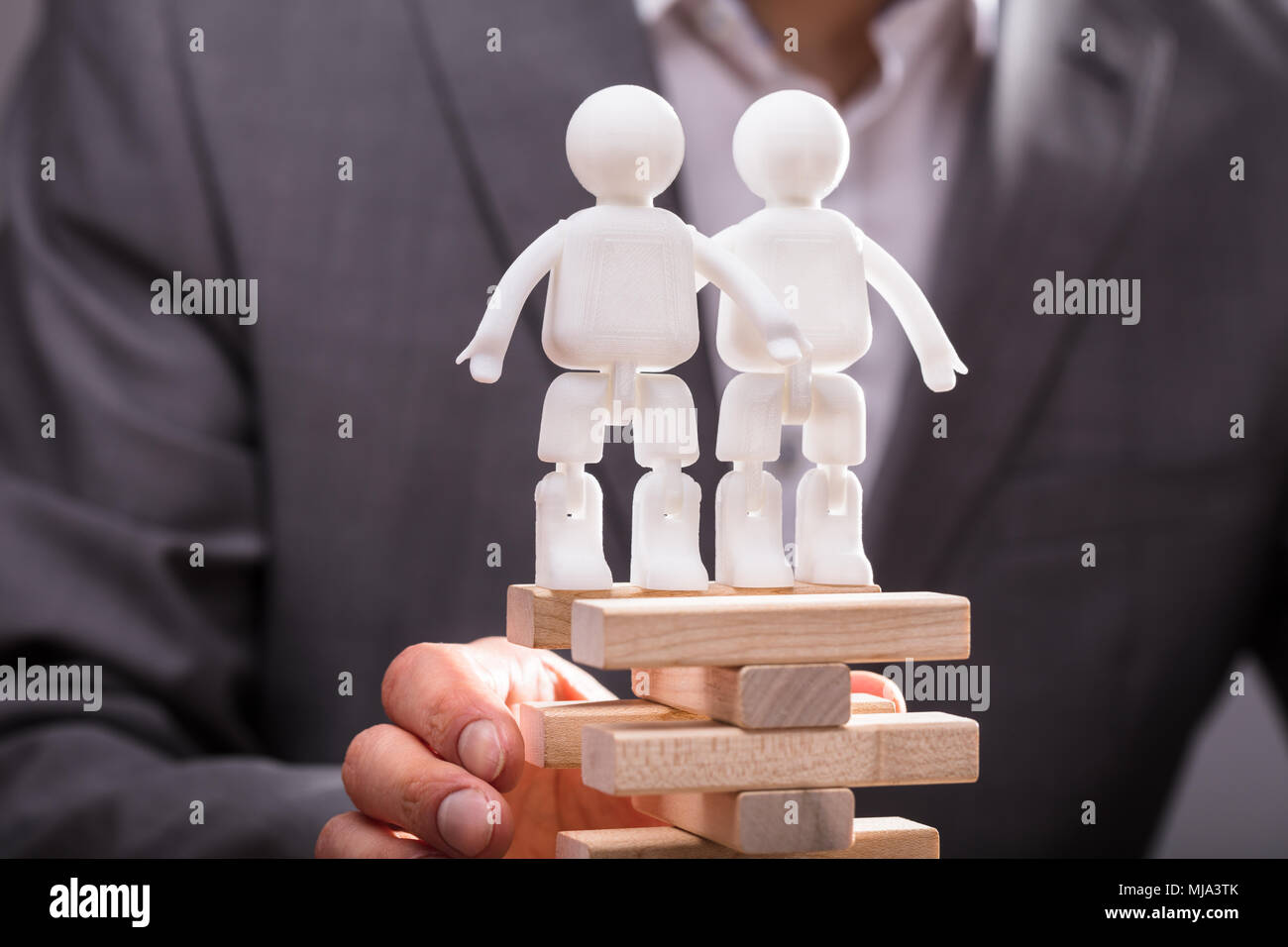 Two Human Figures Standing On Top Of Stacked Wooden Blocks Being ...
