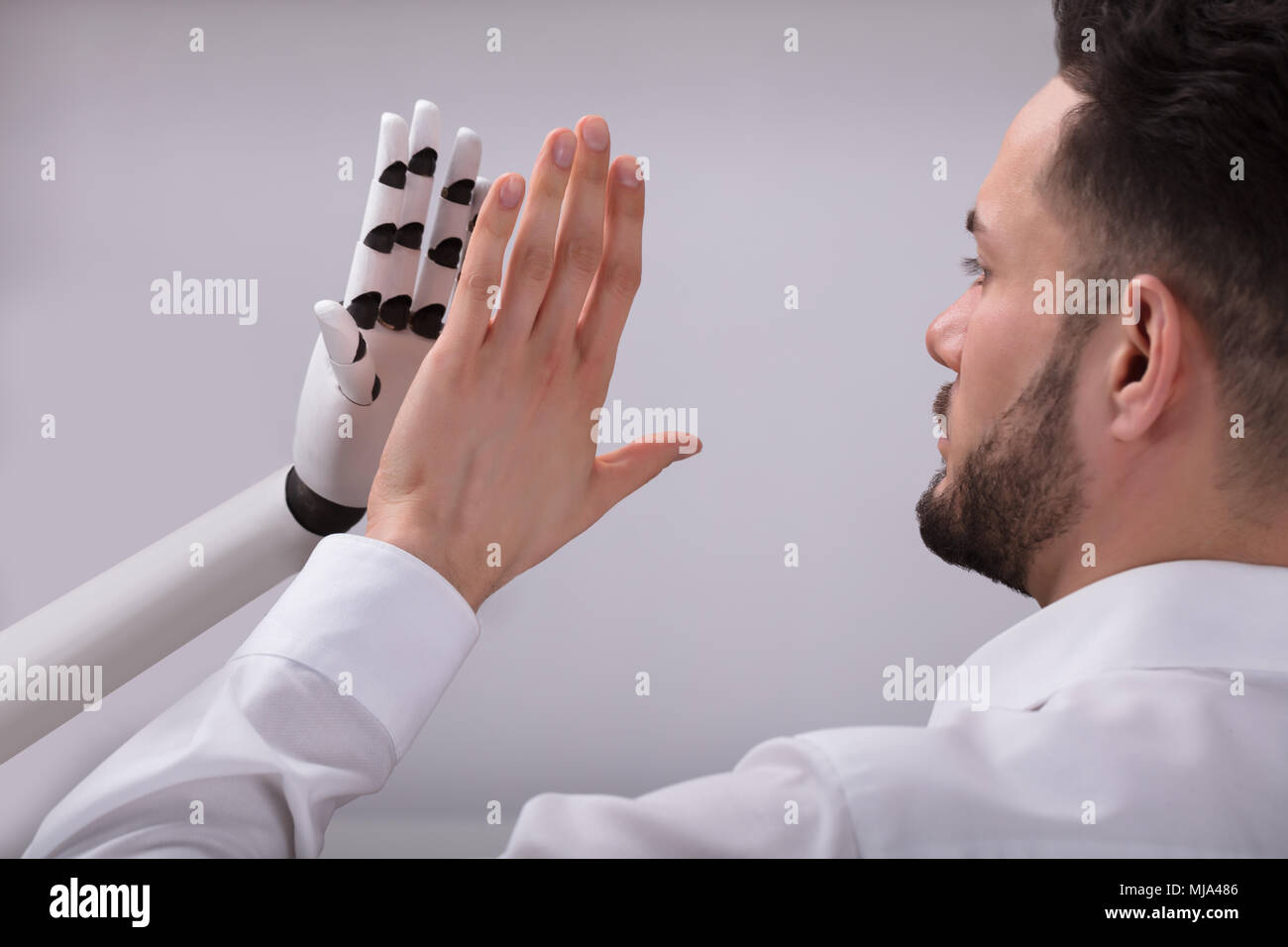 Robot And Man Giving High Five On Grey Background Stock Photo - Alamy