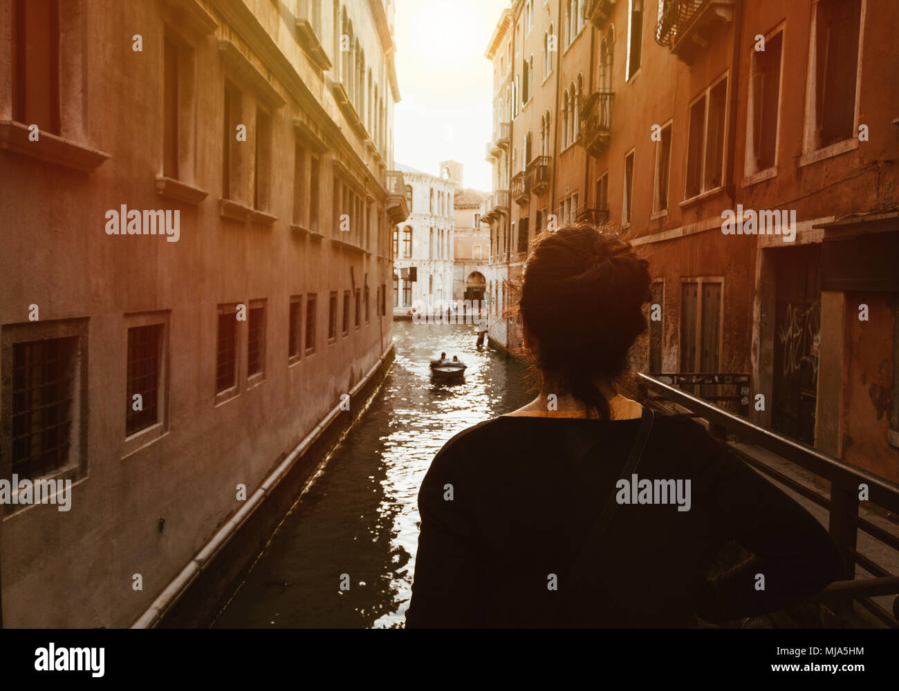 Back view of a sad woman standing on the bridge over the canal at the ...