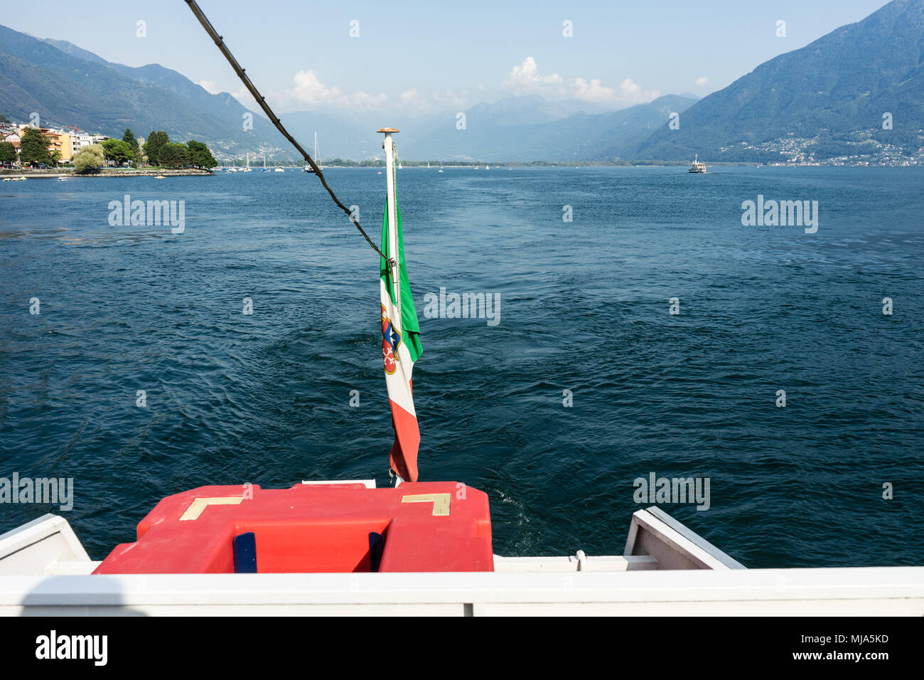 rear view of boat on lago maggiore with flag and blue water view in ...