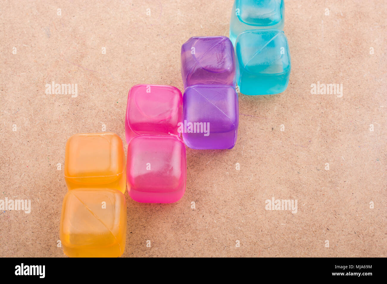 Fake colorful ice cubes on a brown background Stock Photo - Alamy