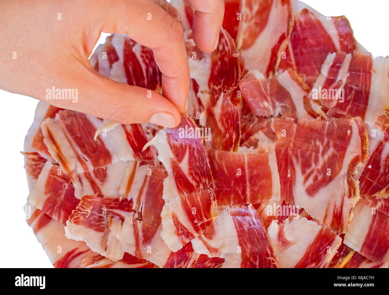 Top view of woman left hand picking serrano ham slice, focus on top of ...