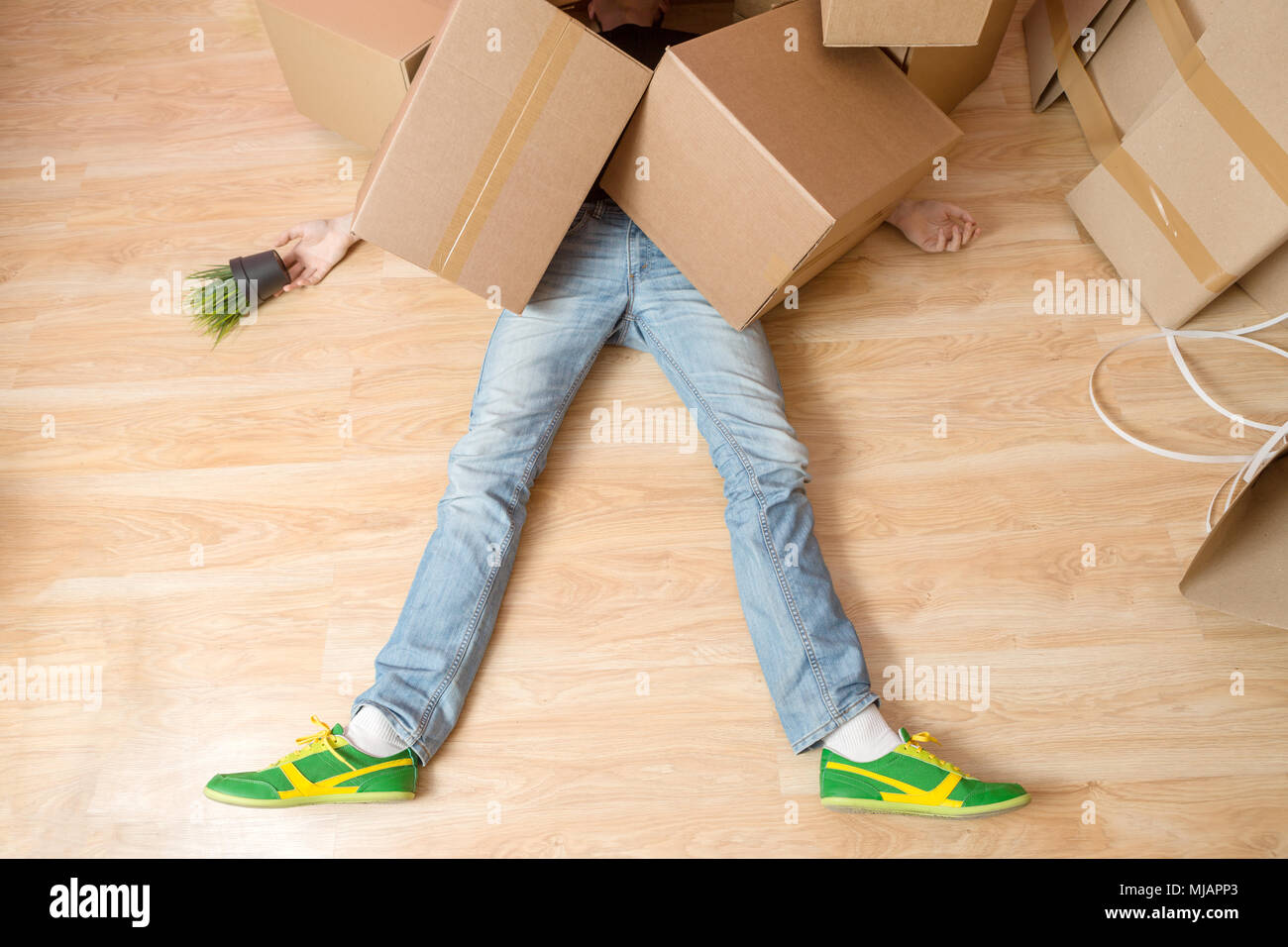 Photo of man in jeans and sneakers lying under cardboard boxes Stock ...