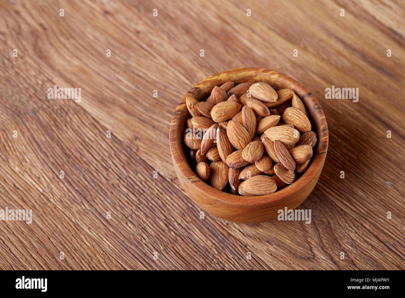 Wooden bowl of almonds on rustic wooden background, top view, close-up ...