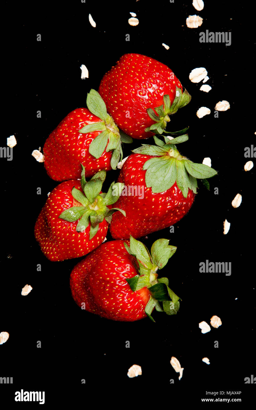 five strawberries on black background Stock Photo - Alamy