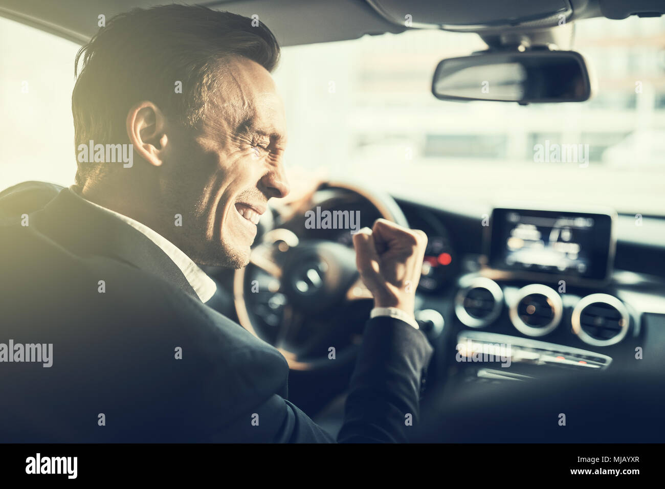 Ecstatic young businessman celebrating success with a fist pump while ...