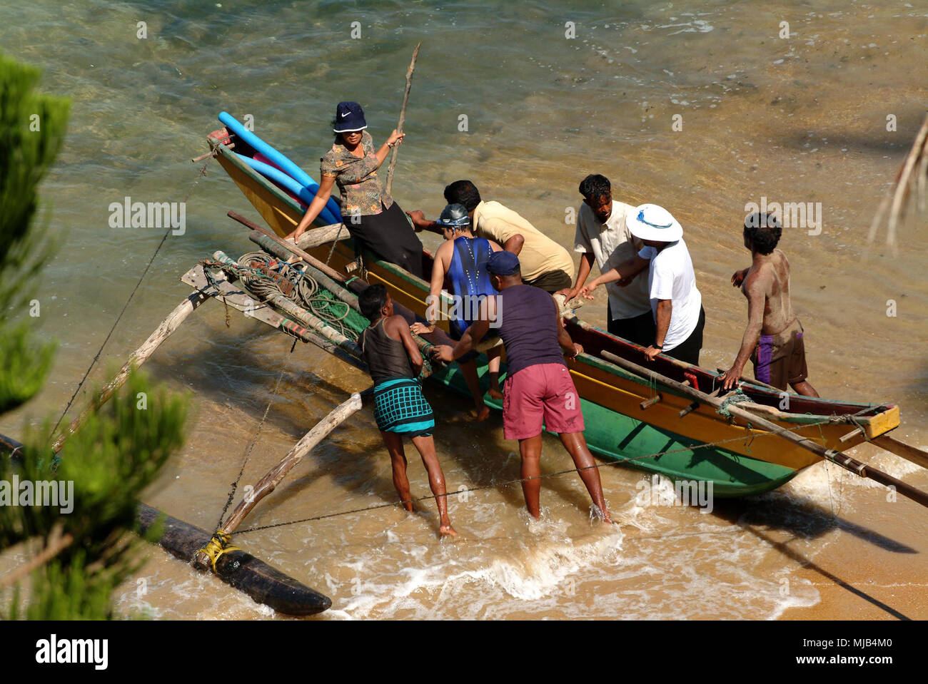Fishermen launch an outrigger boat on the beach at Mount Lavinia ...