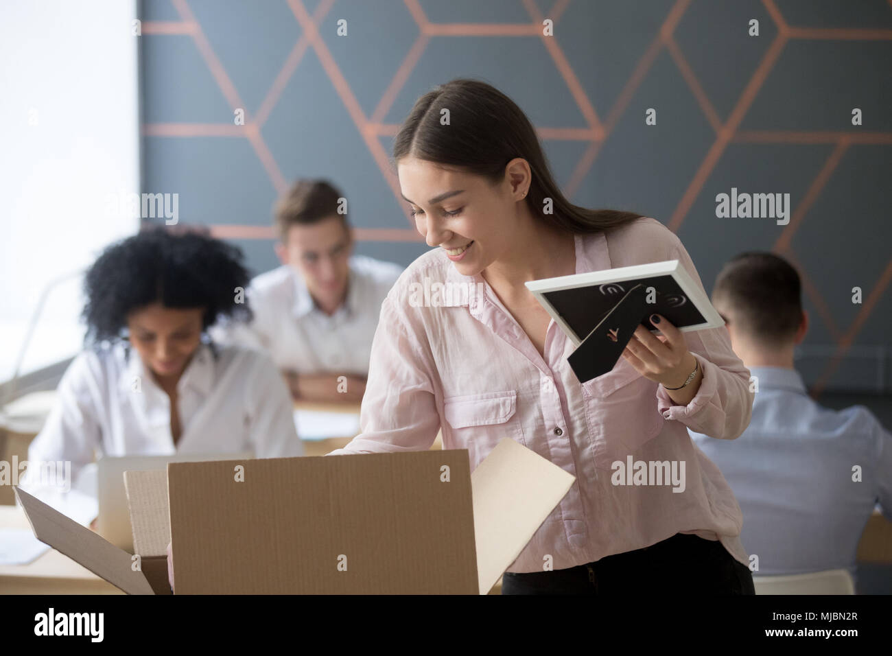 Smiling new female employee unpacking box at workplace in office Stock ...