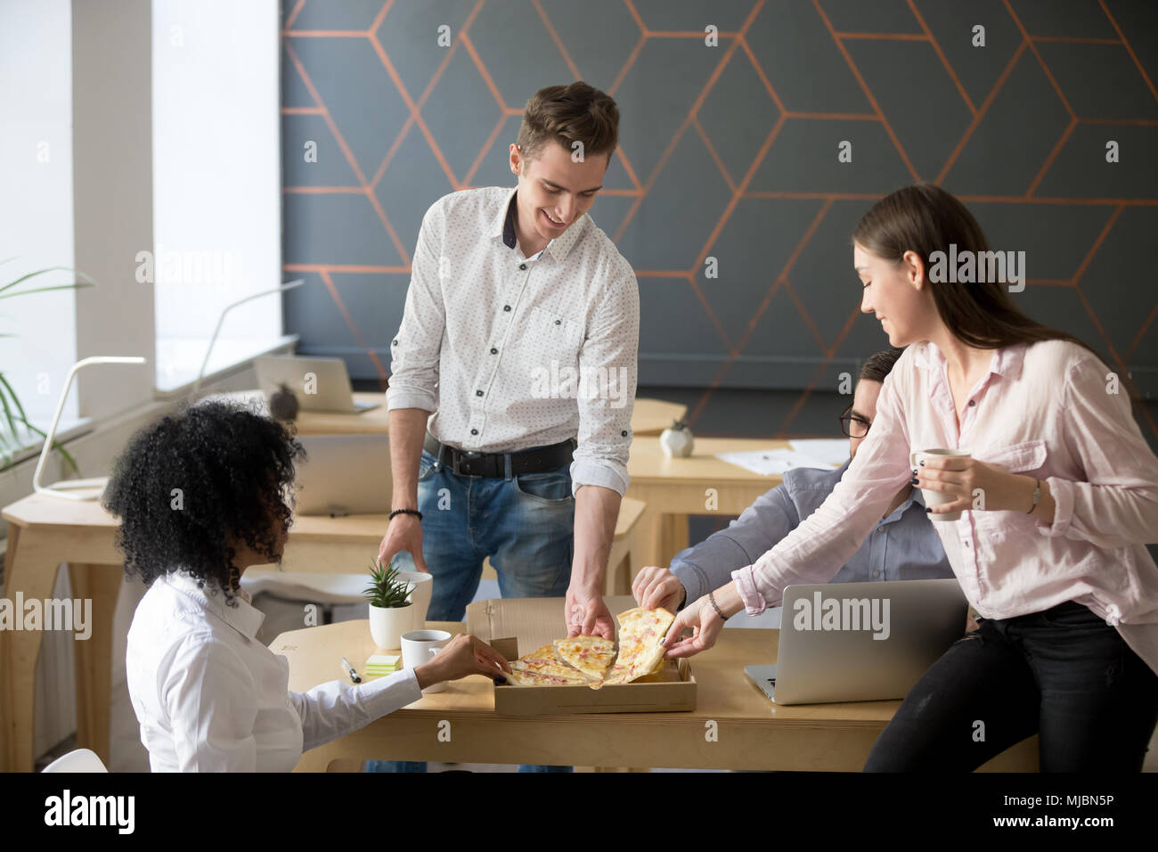 Friendly diverse team eating pizza in office on lunch time Stock Photo ...