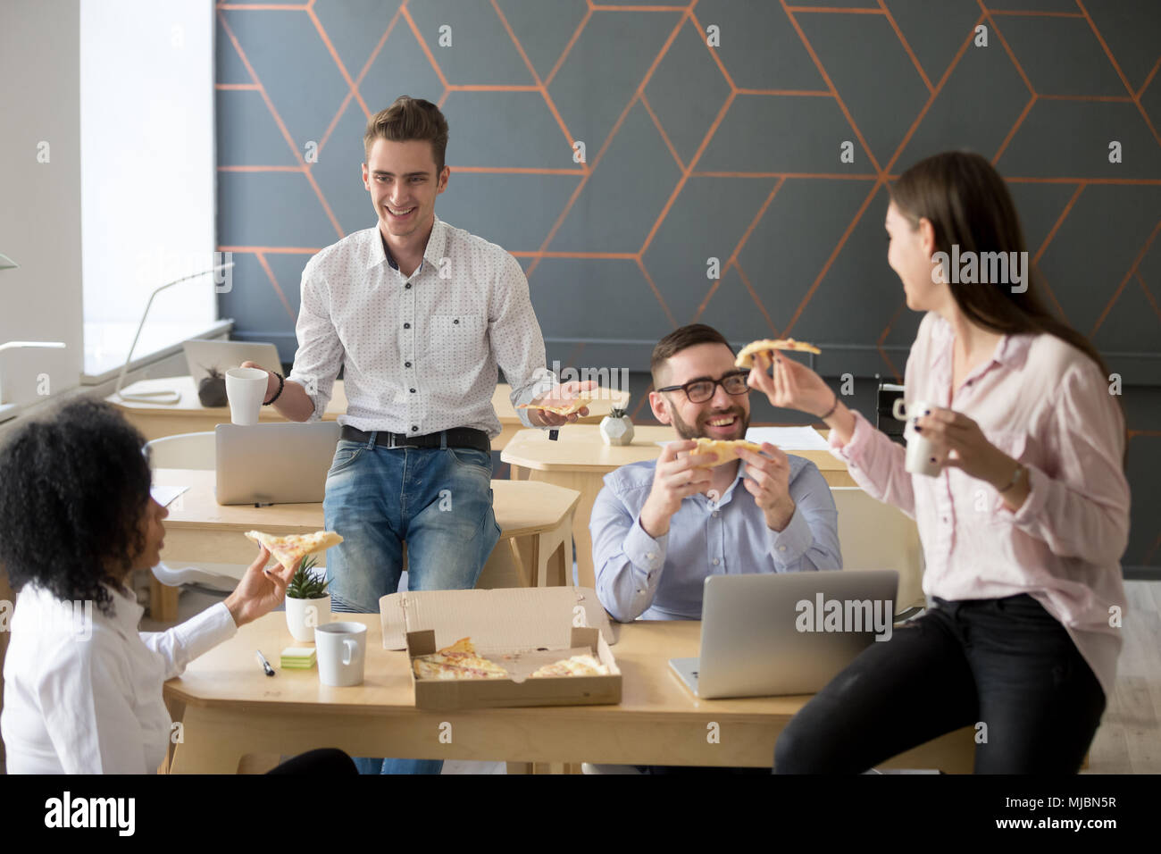 Friendly diverse team talking laughing eating pizza together in Stock Photo - Alamy