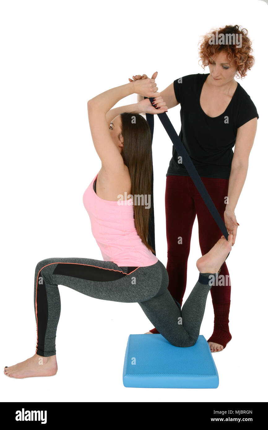 Yoga teacher helping young girl to do yoga asana Ashwa Sanchalanasana ...