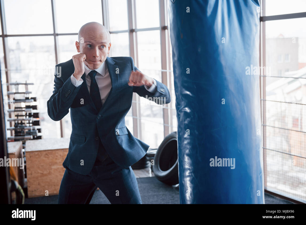 An angry bald businessman beats a boxing pear in the gym. concept of ...