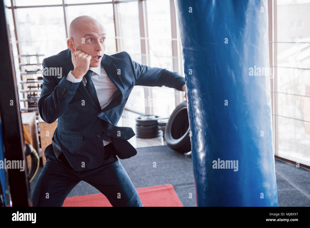 An angry bald businessman beats a boxing pear in the gym. concept of ...