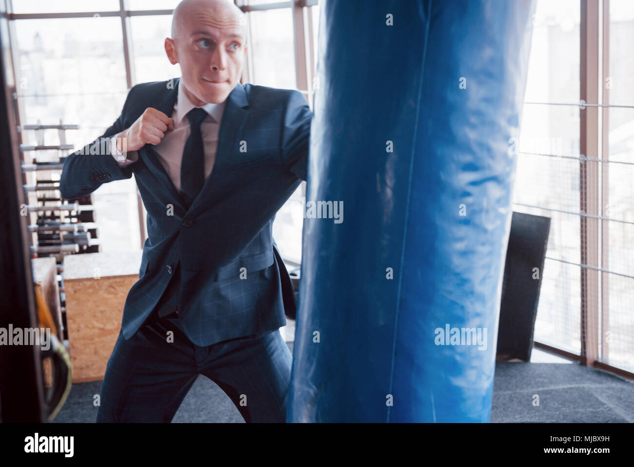 An angry bald businessman beats a boxing pear in the gym. concept of ...