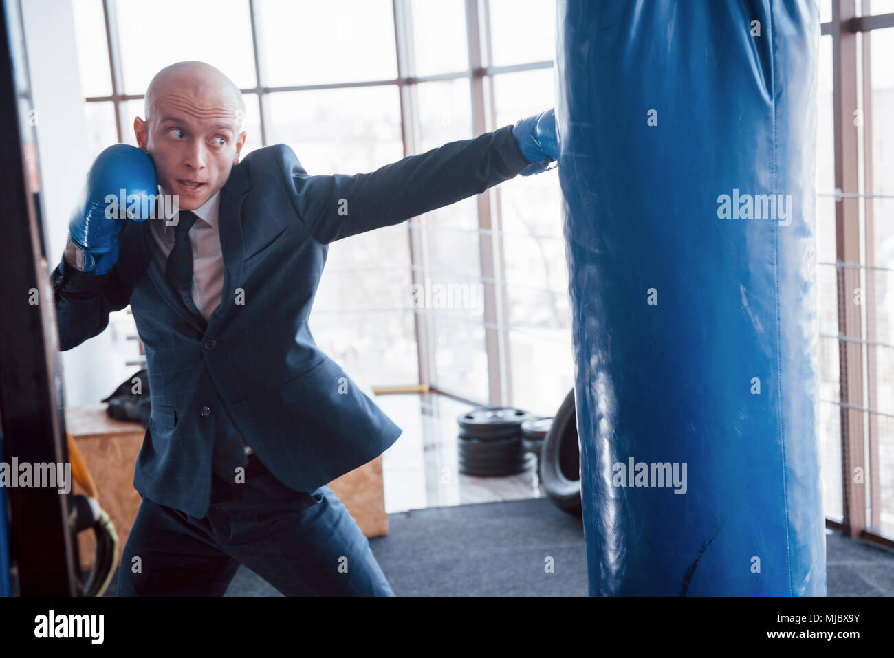 An angry bald businessman beats a boxing pear in the gym. concept of ...