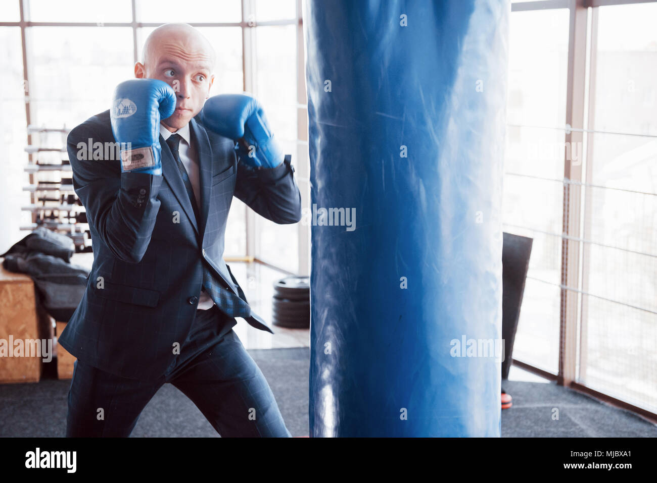 An angry bald businessman beats a boxing pear in the gym. concept of ...