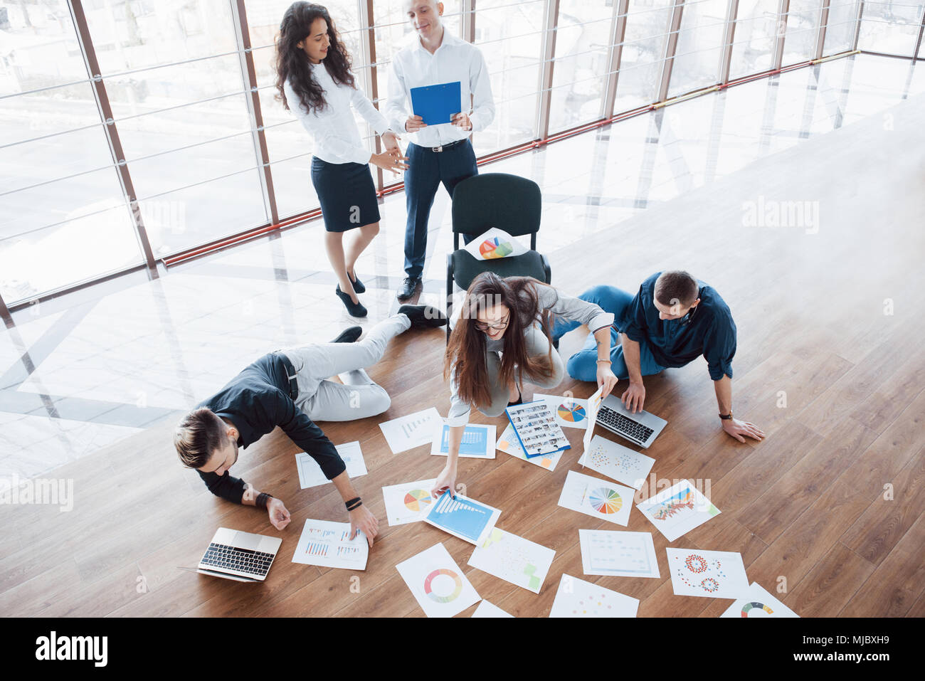 Planning strategy together. Business team looking at papers on floor ...