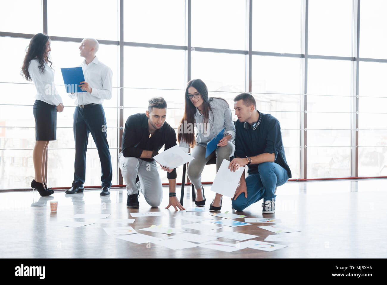 Planning strategy together. Business team looking at papers on floor ...