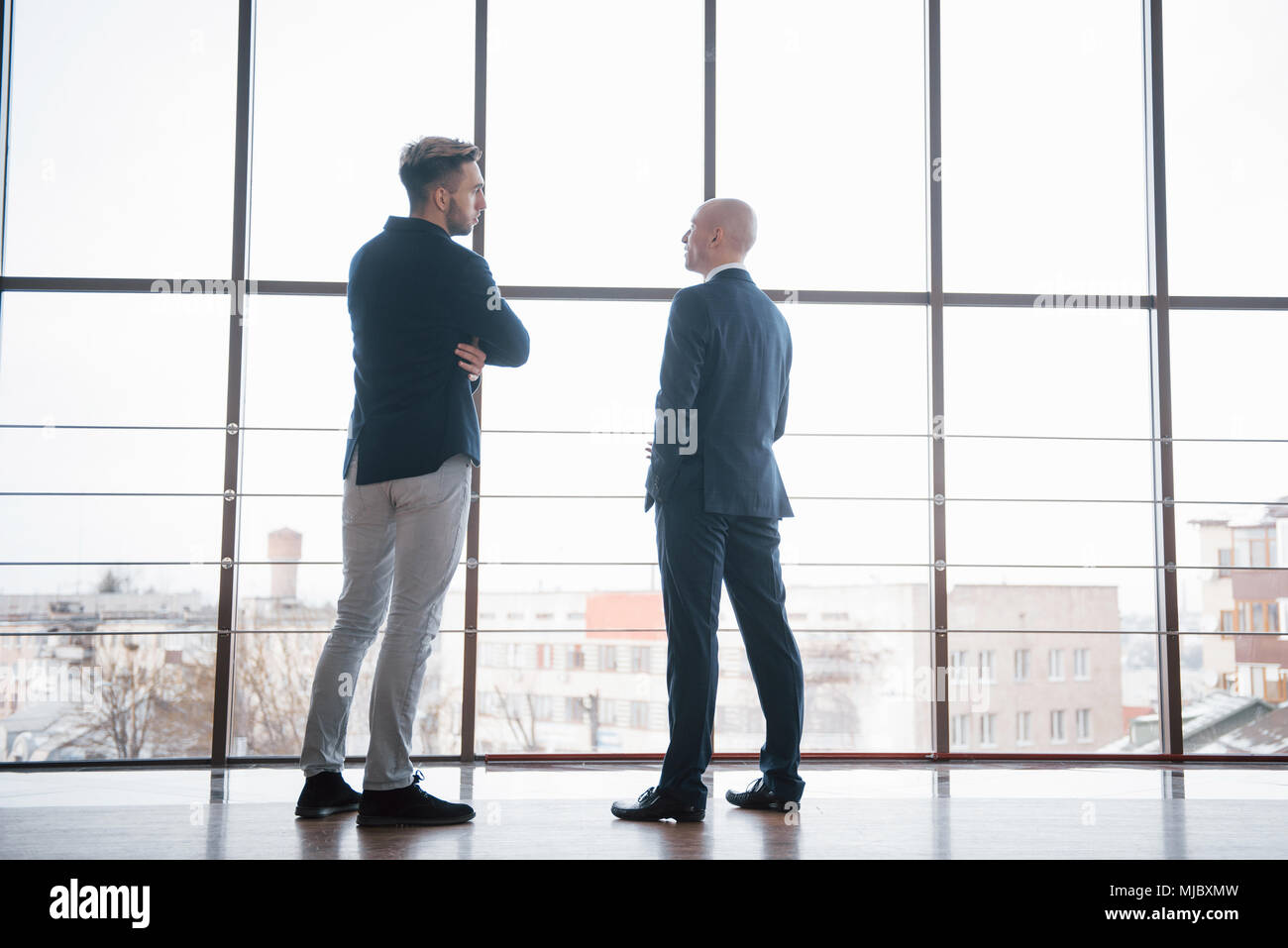 Two businessmen deep in discussion together while standing in an office ...