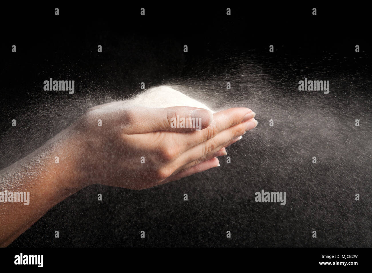 flour blowing of hands of woman on black background like a storm Stock ...