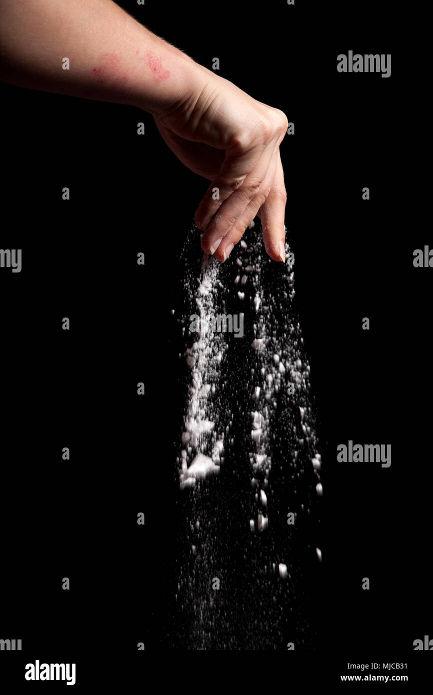 flour falling down of woman hand on black background Stock Photo - Alamy