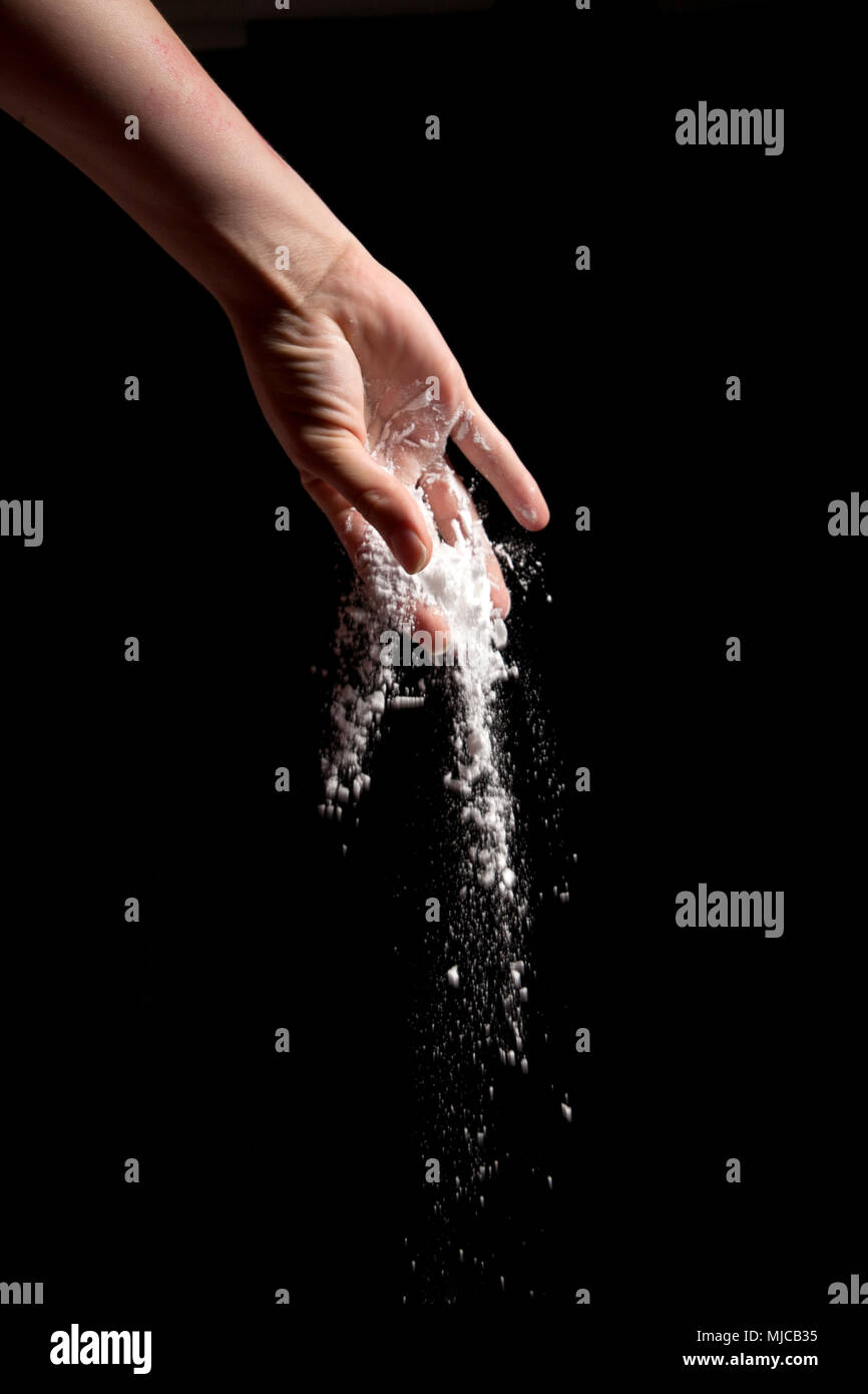 flour falling down of woman hand on black background Stock Photo - Alamy