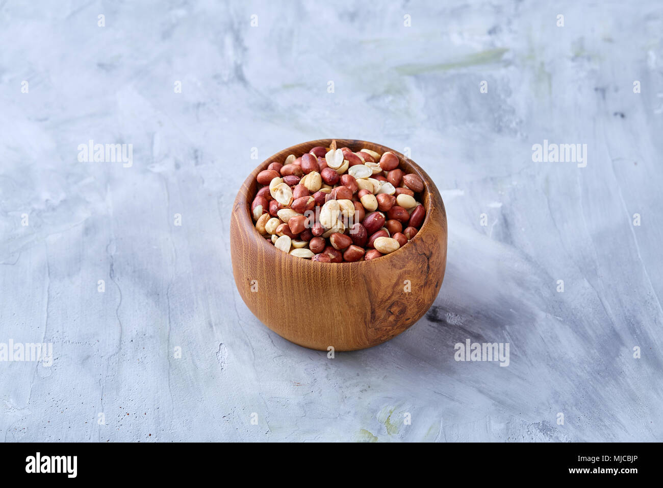 Mix of raw shelled peanuts in wooden plate isolated over white textured ...