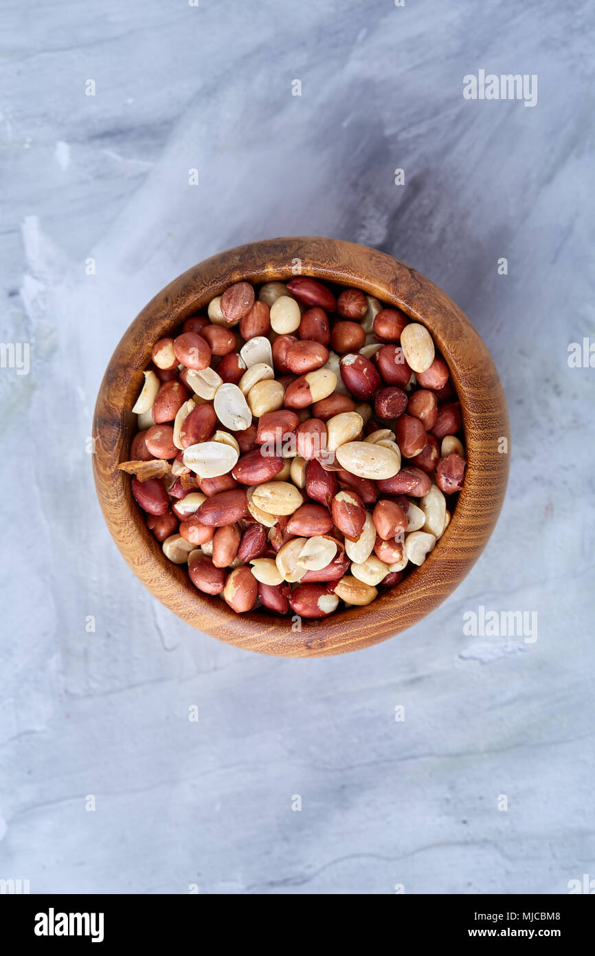 Mix of raw shelled peanuts in wooden plate isolated over white textured ...