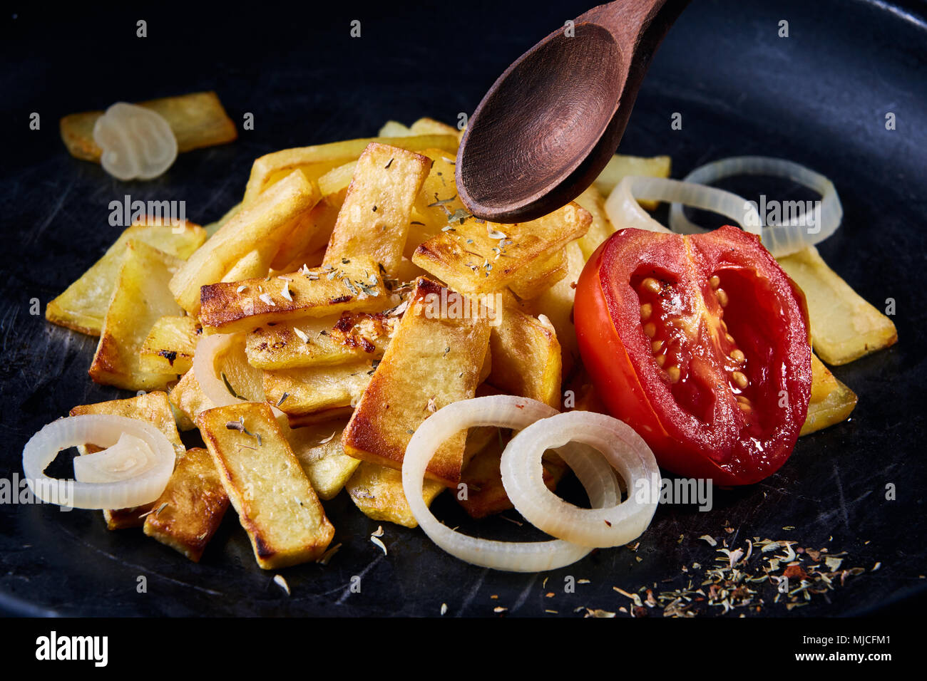 Delicious homemade spicy fries with onion and grilled tomato half over ...