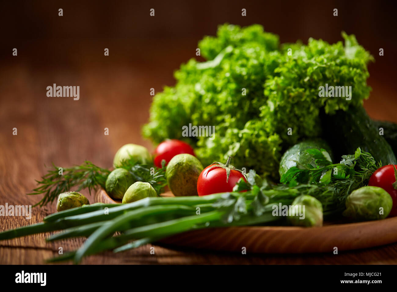 Vegetarian still life of fresh vegetables on wooden plate over rustic ...