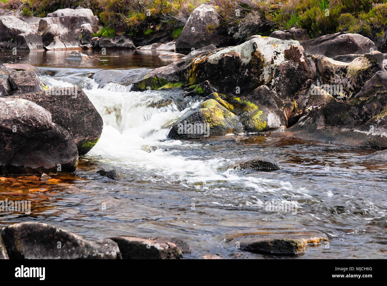 Small Scottish Highlands burn tumbling through the rocks and boulders ...
