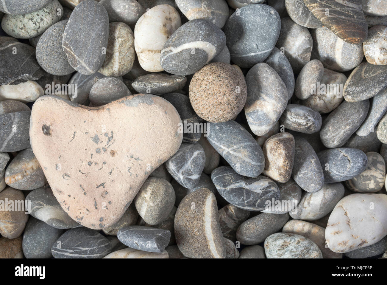 Heart-shaped stone on pebble beach Stock Photo - Alamy