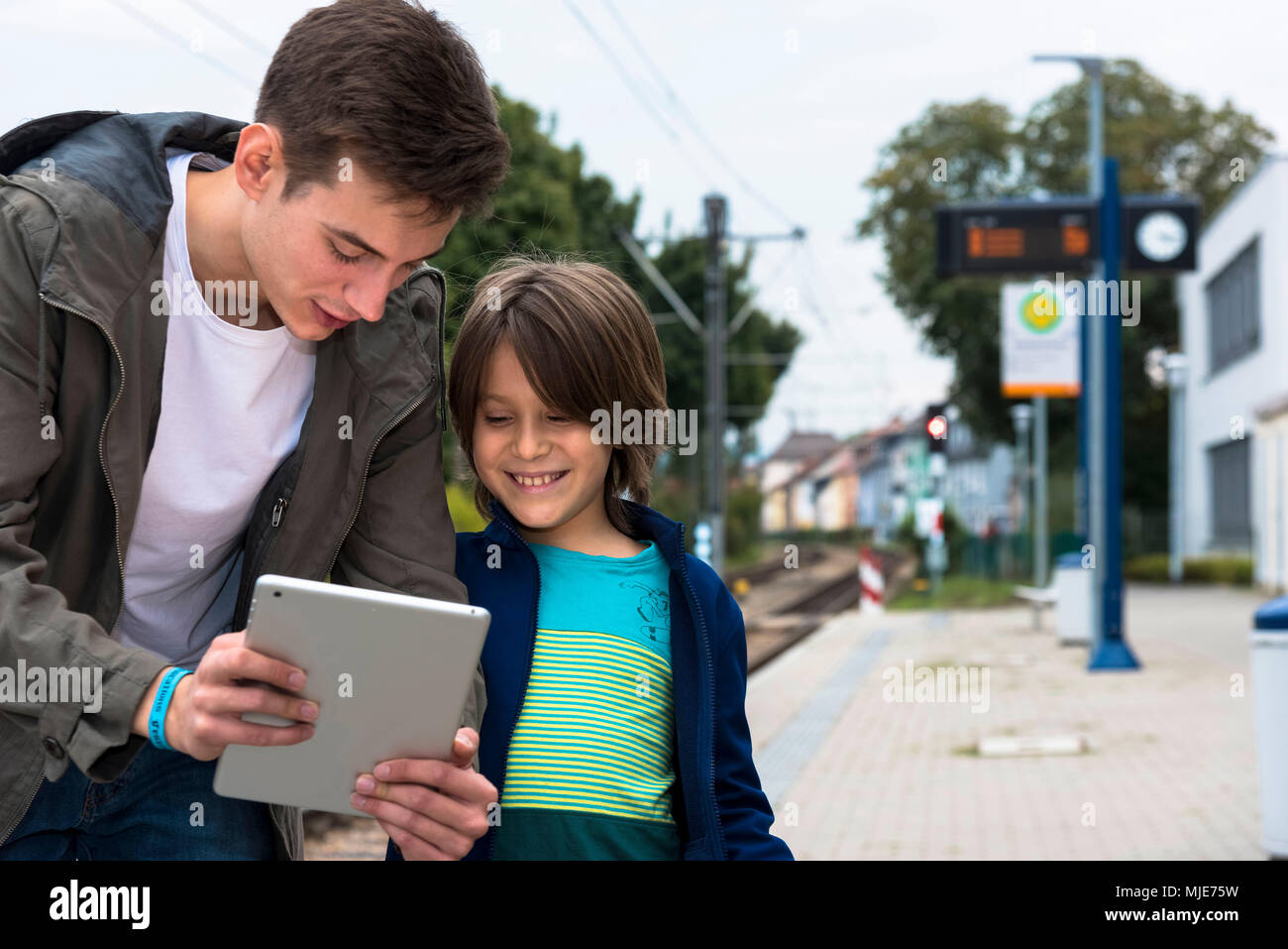 young man and child with tablet at the train platform Stock Photo - Alamy