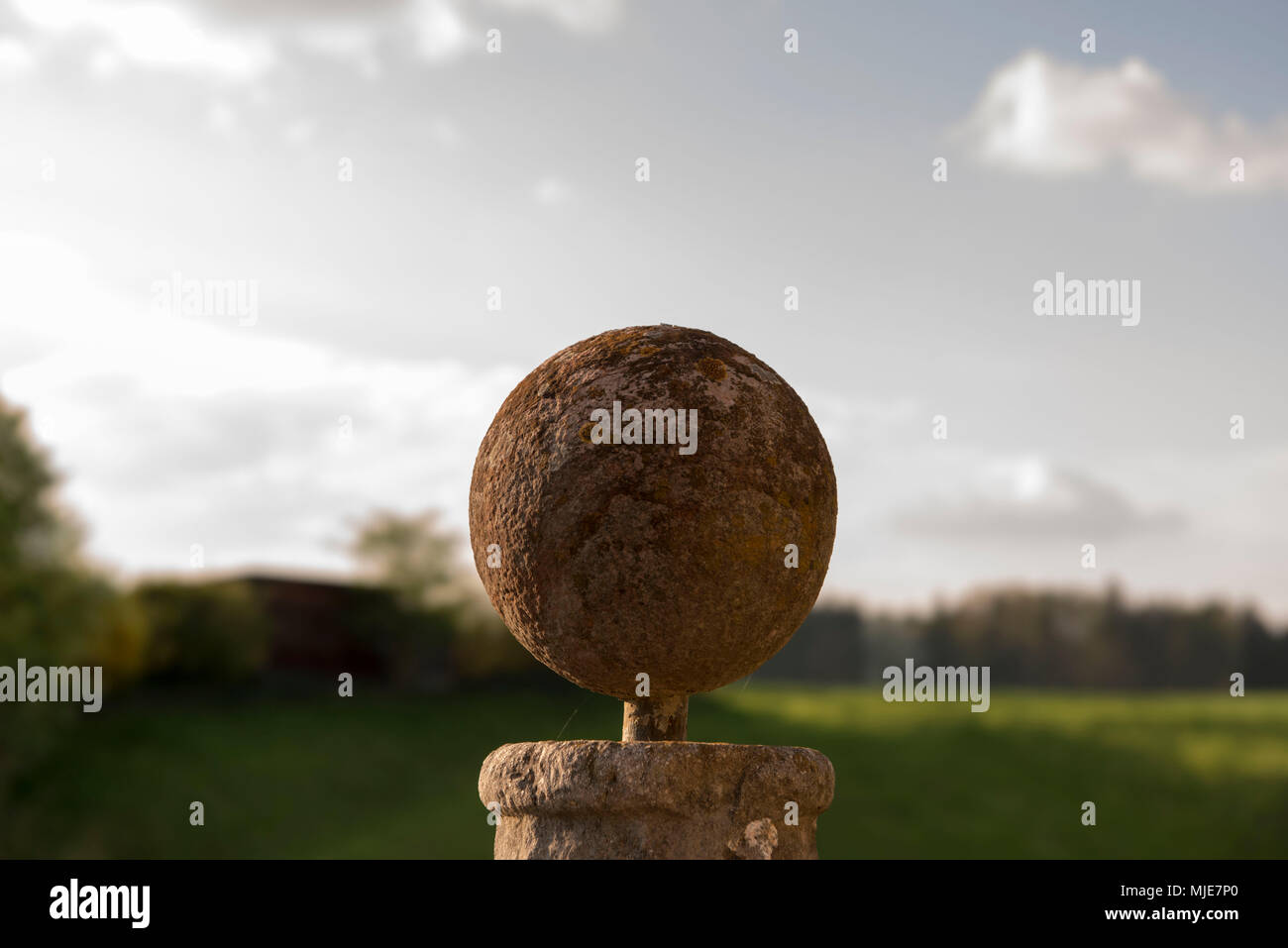 Pillar with ball in front of blurred landscape Stock Photo - Alamy