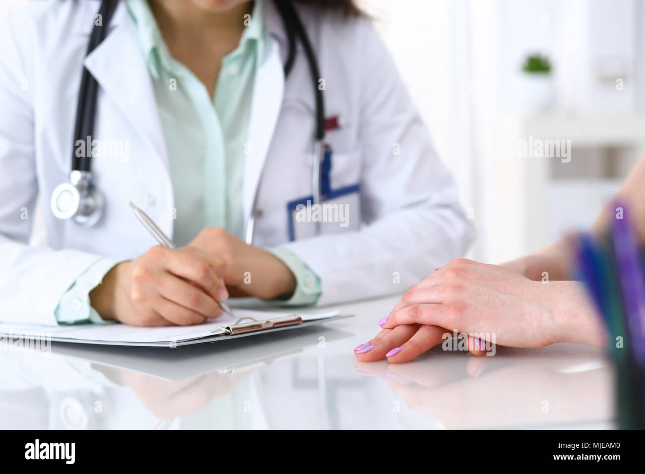 Female doctor filling up an application form while consulting patient ...