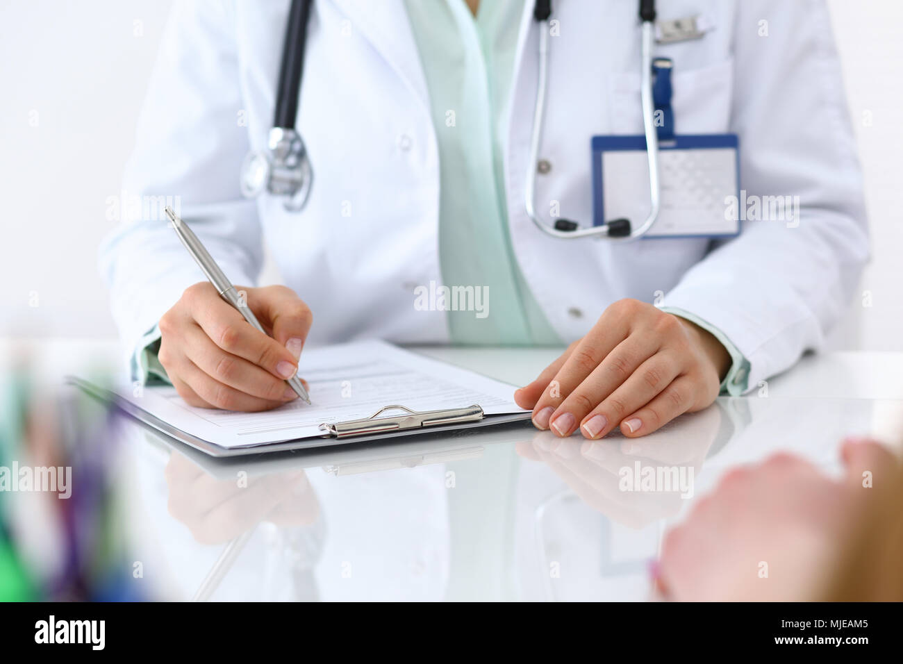 Female doctor filling up an application form while consulting patient ...