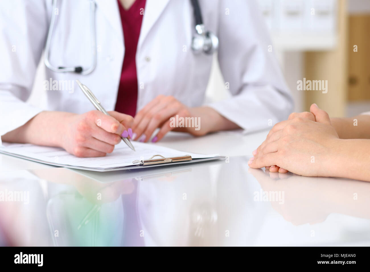 Female doctor filling up an application form while consulting patient ...