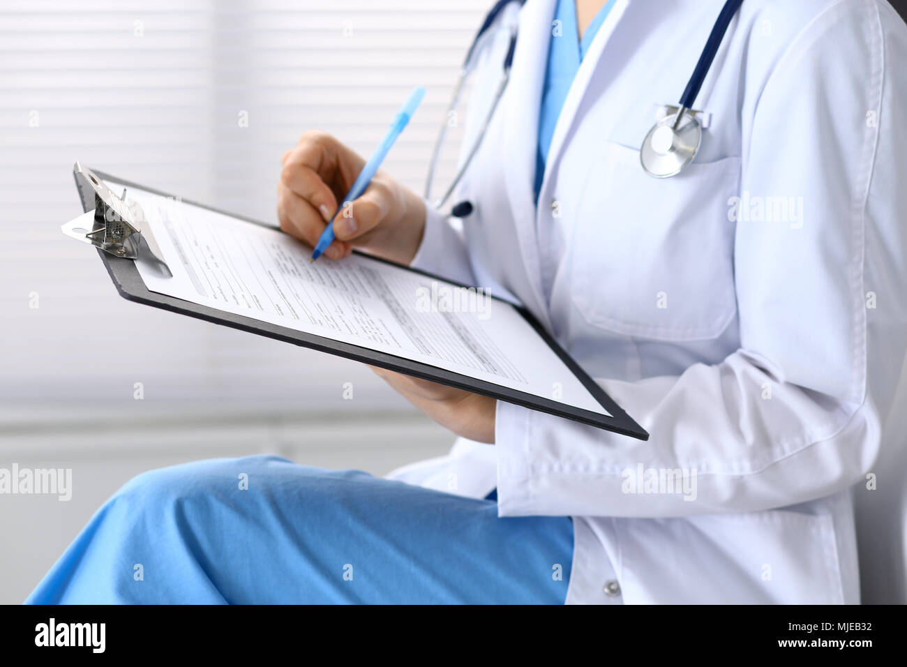 Female doctor filling up medical form on clipboard closeup. Physician ...